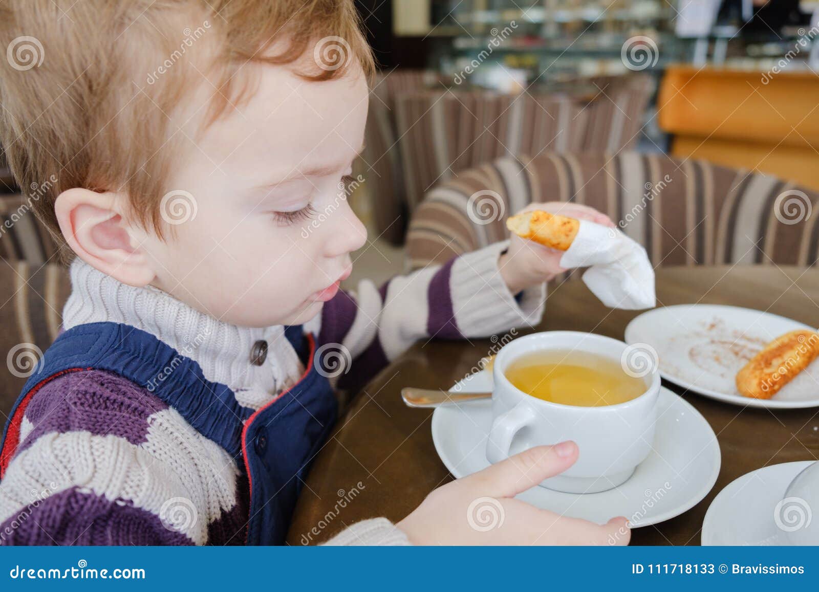Little Boy Drinks Tea in the Cafe with Cookies and Cakes from Cup ...