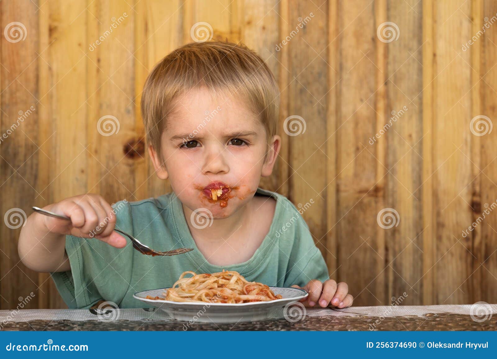 A Little Boy is Eating Spaghetti. His Face is Smeared with Ketchup ...
