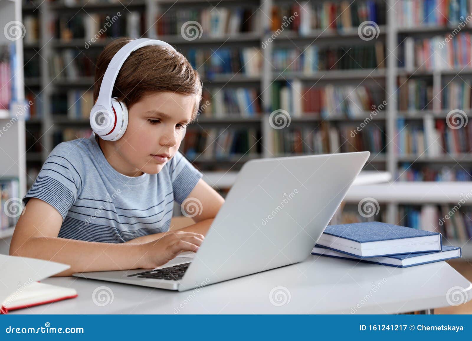 Little Boy with Headphones Reading Book Using Laptop Stock Image ...