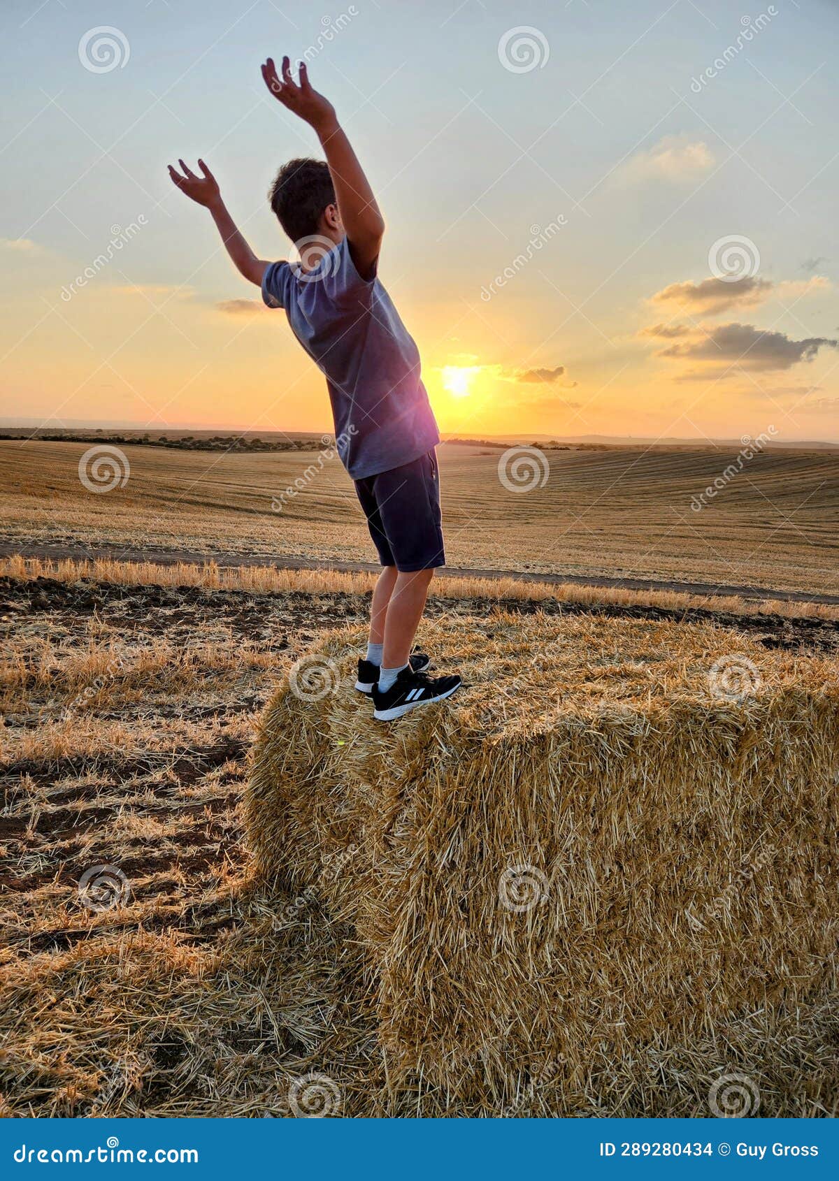 Little Boy Jumping on a Haystack at Sunset in the Countryside. Stock ...