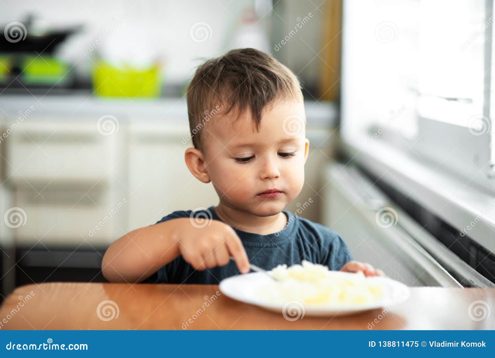 A Little Boy in the Kitchen Greedily Eats Rice with a Spoon Stock Image ...