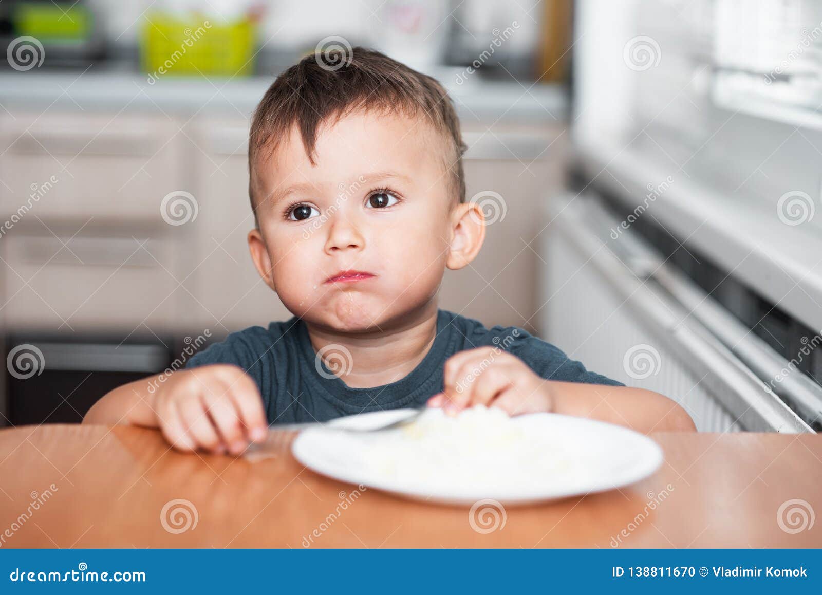 A Little Boy in the Kitchen Greedily Eats Rice with a Spoon Stock Photo ...
