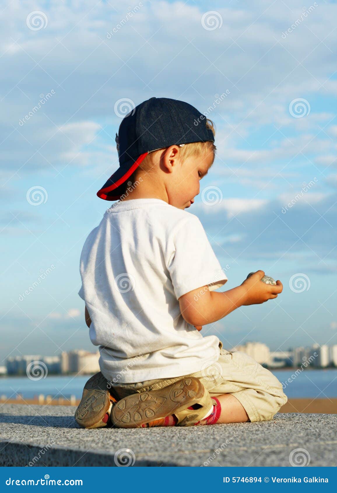 Little Boy Kneels On The Quay Stock Photo - Image: 5746894