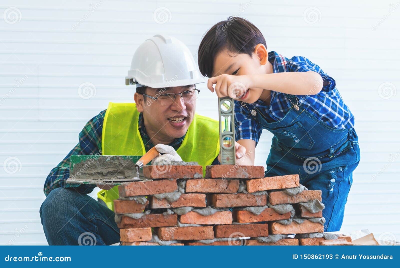 Little Boy Learning How To Lay Down Brick Work from His Builder Father ...