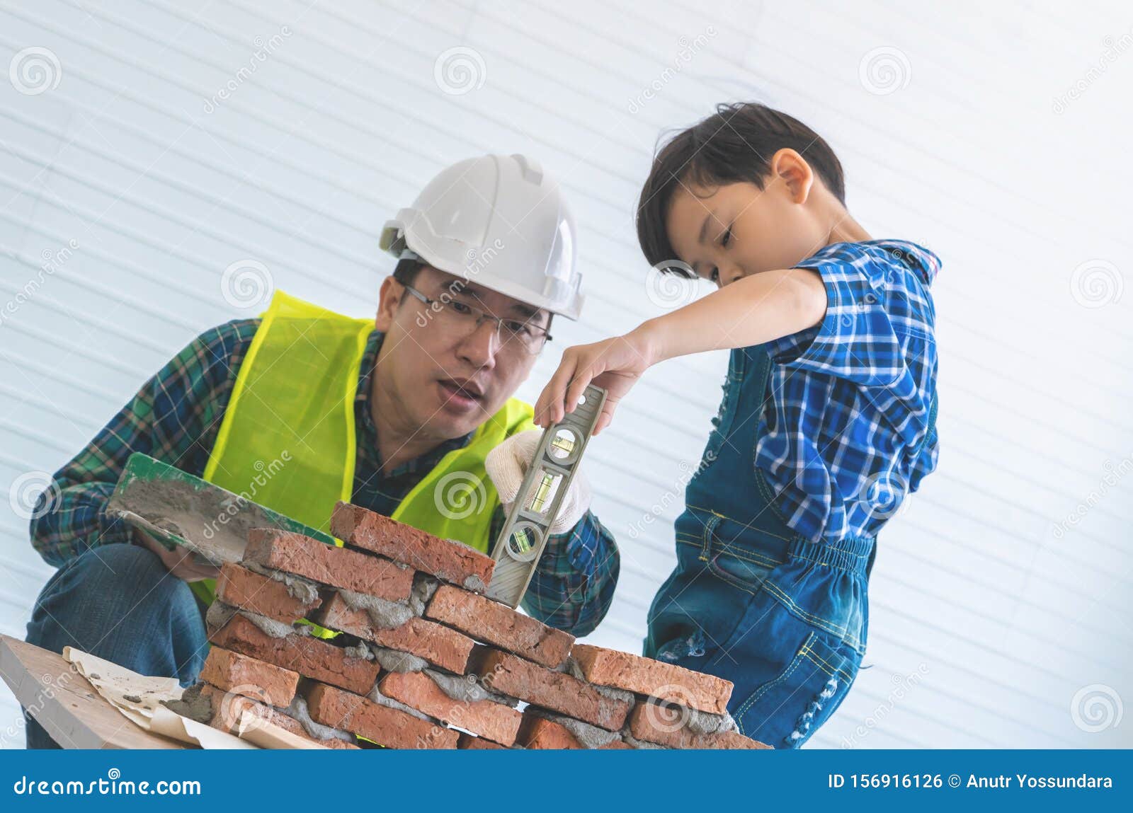 Little Boy Learning How To Lay Down Brick Work from His Builder Father ...