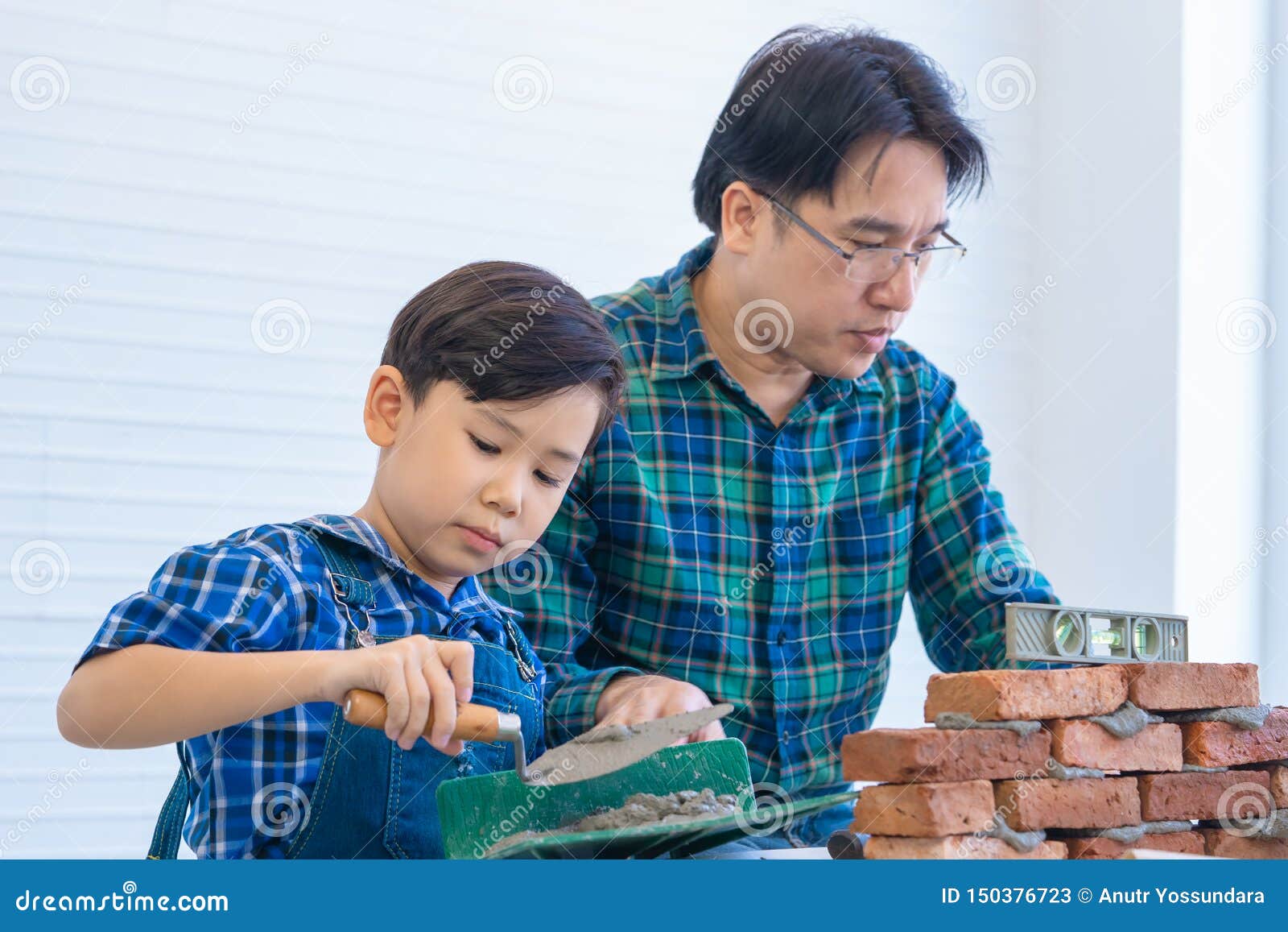 Little Boy Learning How To Lay Down Brick Work from His Builder Father ...
