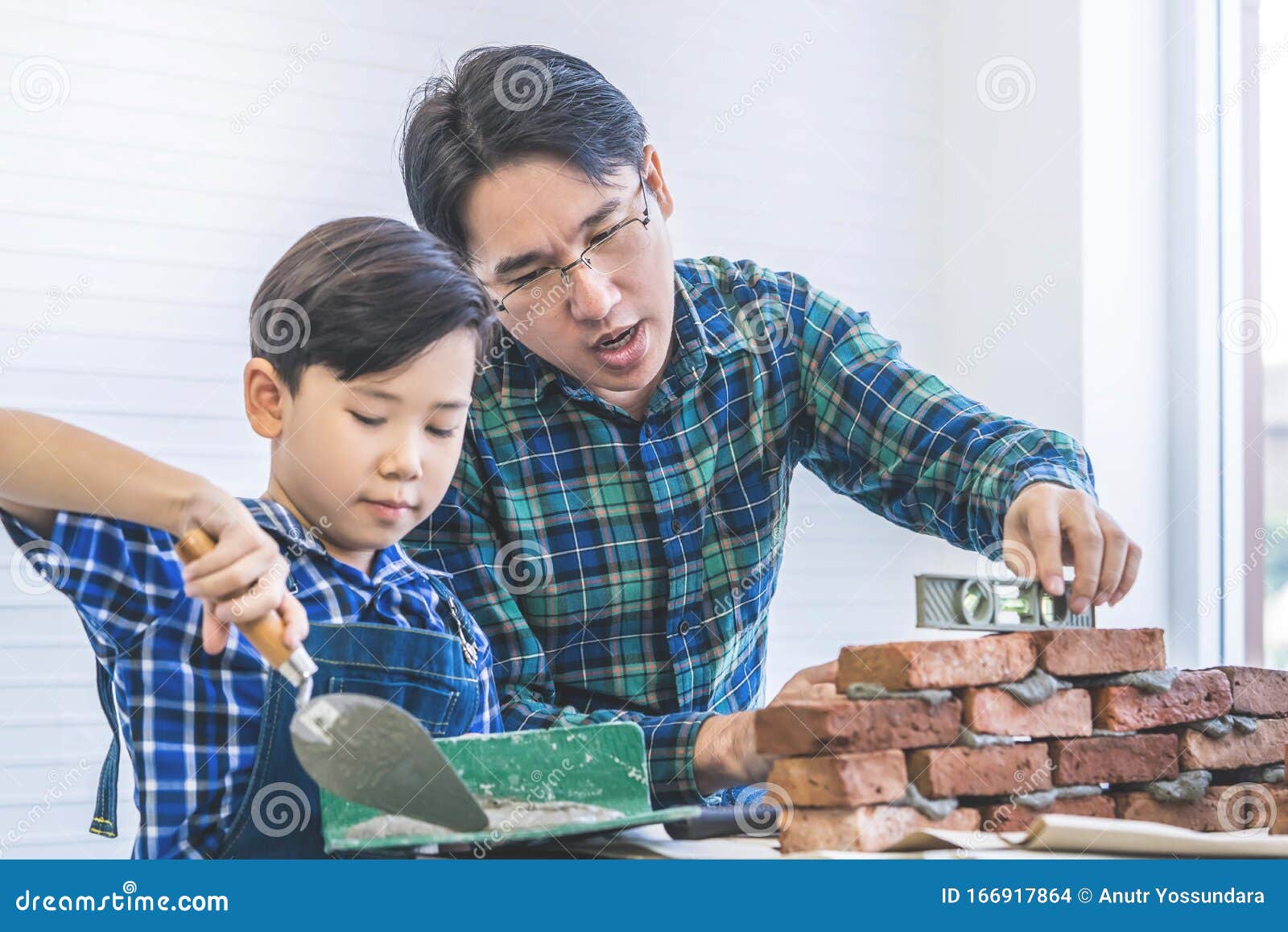 Little Boy Learning How To Lay Down Brick Work from His Builder Father ...