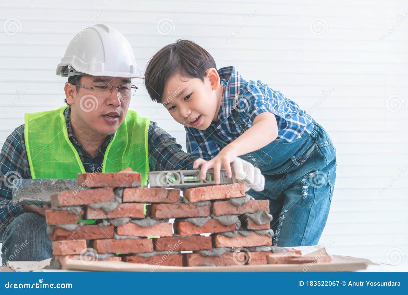 Little Boy Learning How To Lay Down Brick Work from His Builder Father ...