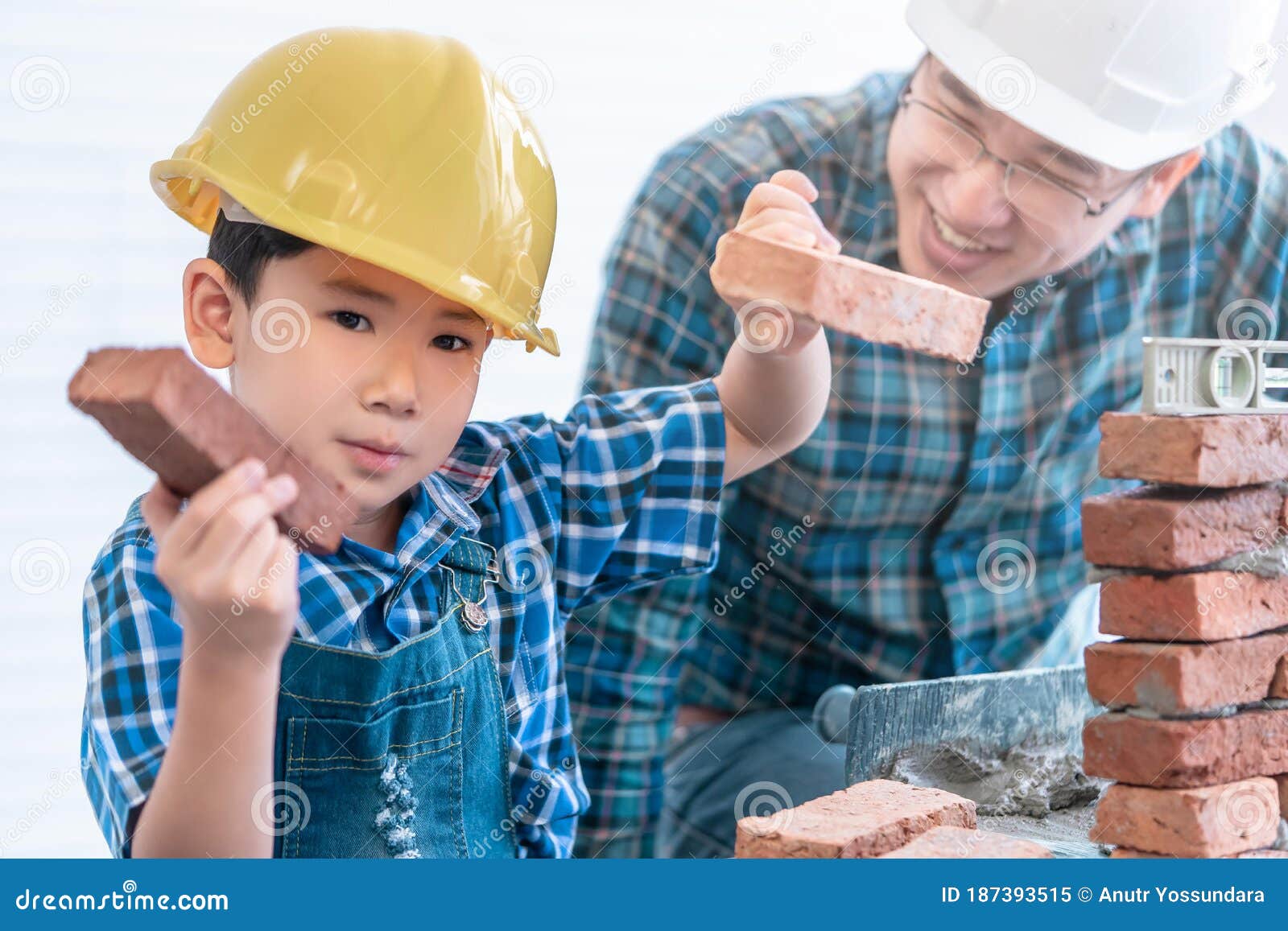 Little Boy Learning How To Lay Down Brick Work from His Builder Father ...