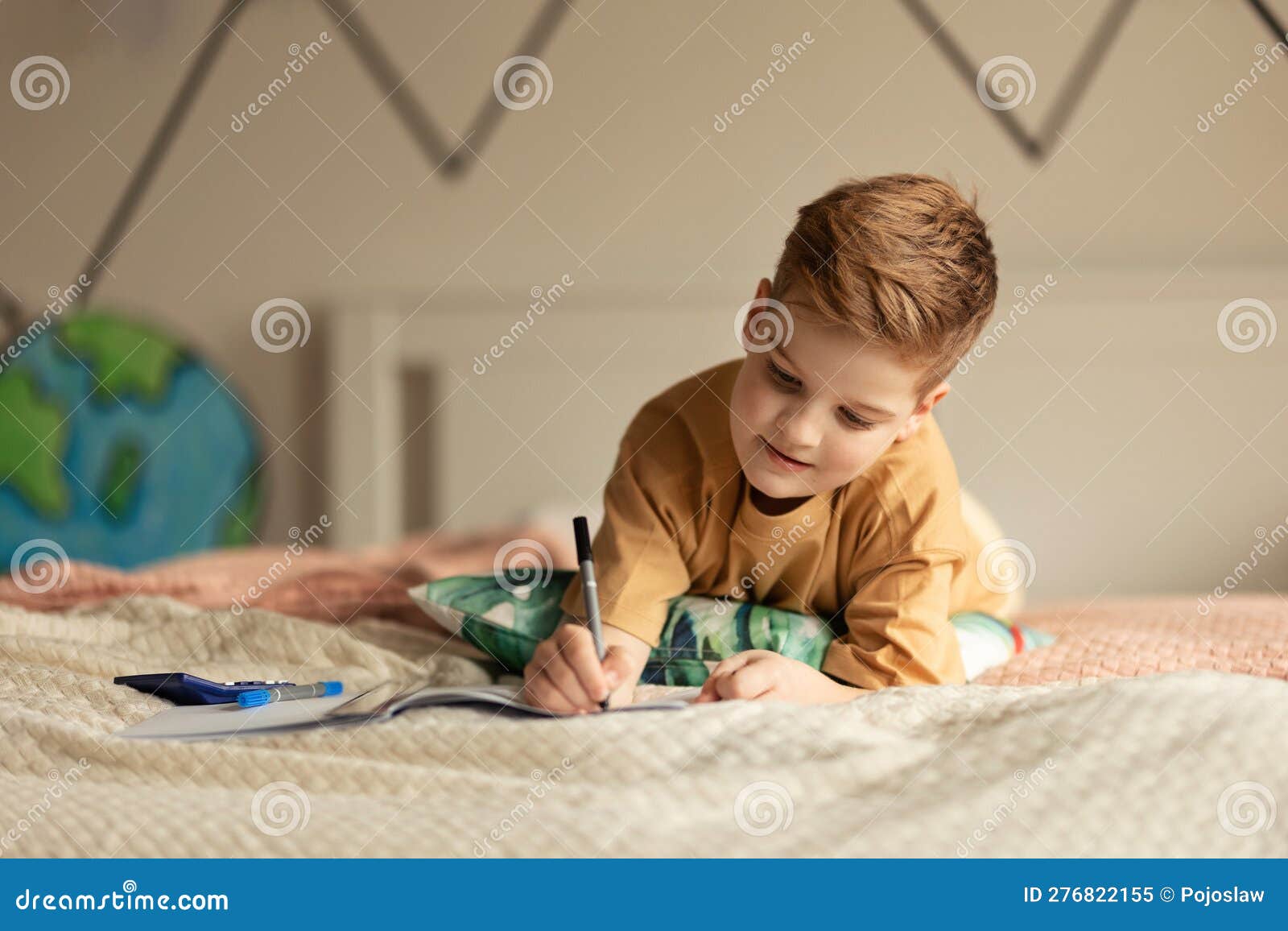 Little Boy Lying on a Bed and Doing His Homework. Stock Image - Image ...