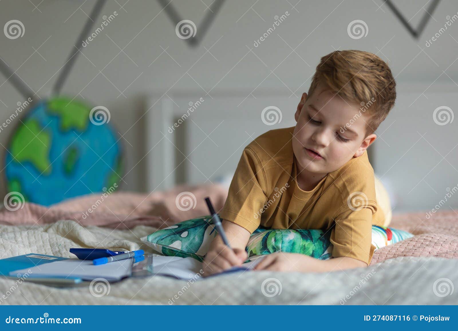 Little Boy Lying on a Bed and Doing His Homework. Stock Photo - Image ...