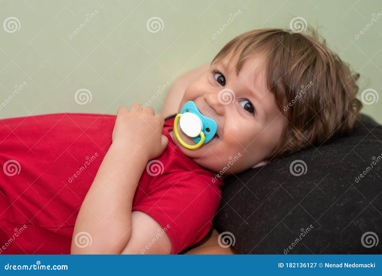 The Little Boy is Lying on a Pillow with a Pacifier and Laughing Stock ...
