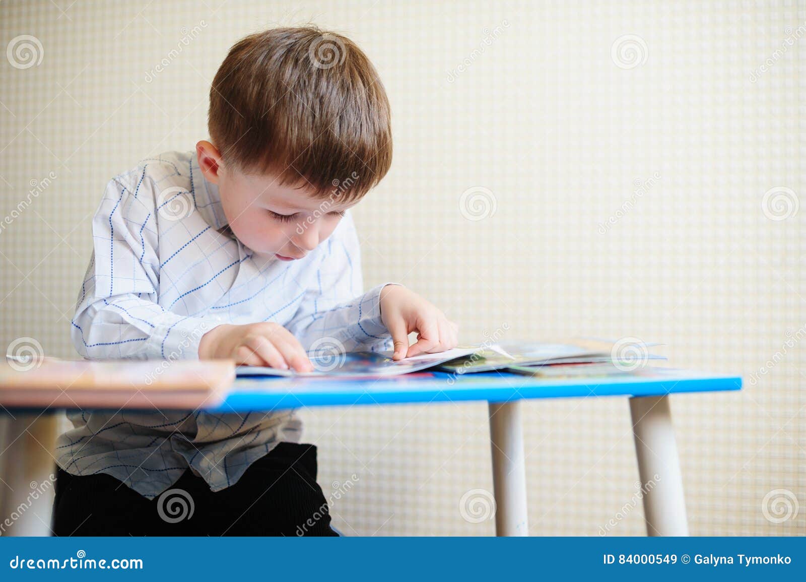 Little Boy is Sitting at His Desk and Reads a Book Stock Image - Image ...
