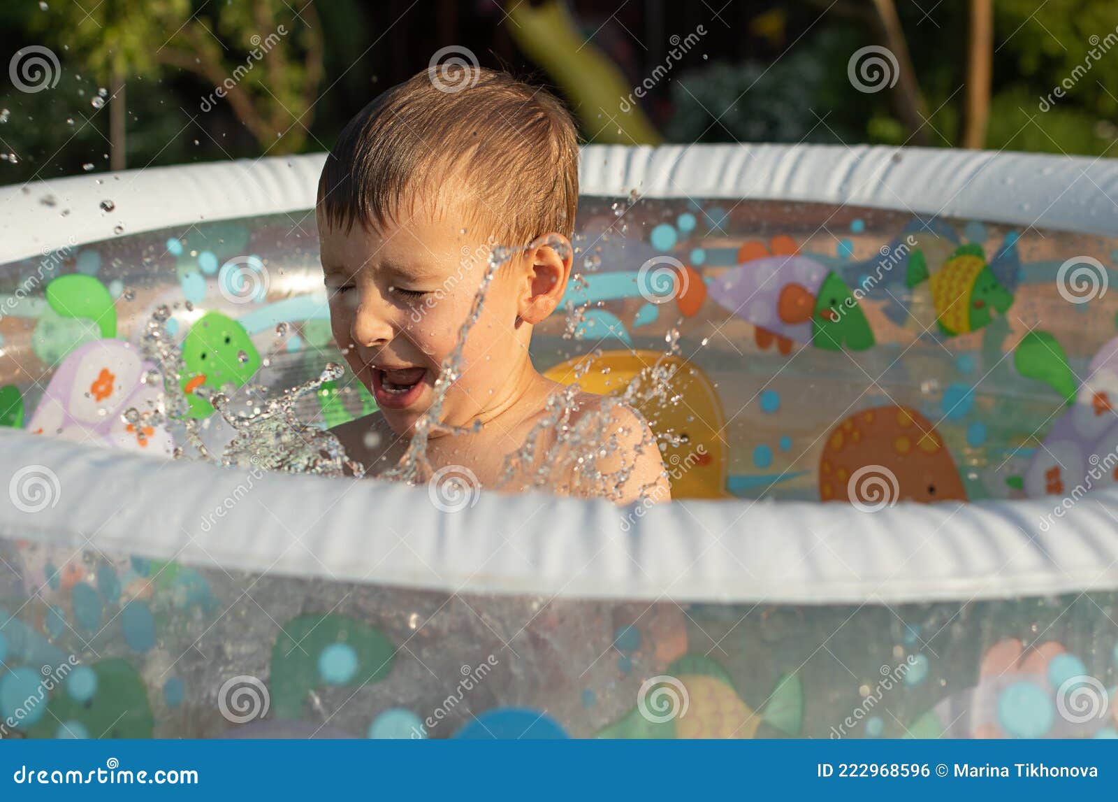 Little Boy Splashes in an Inflatable Pool. Squints from the Spray Stock ...