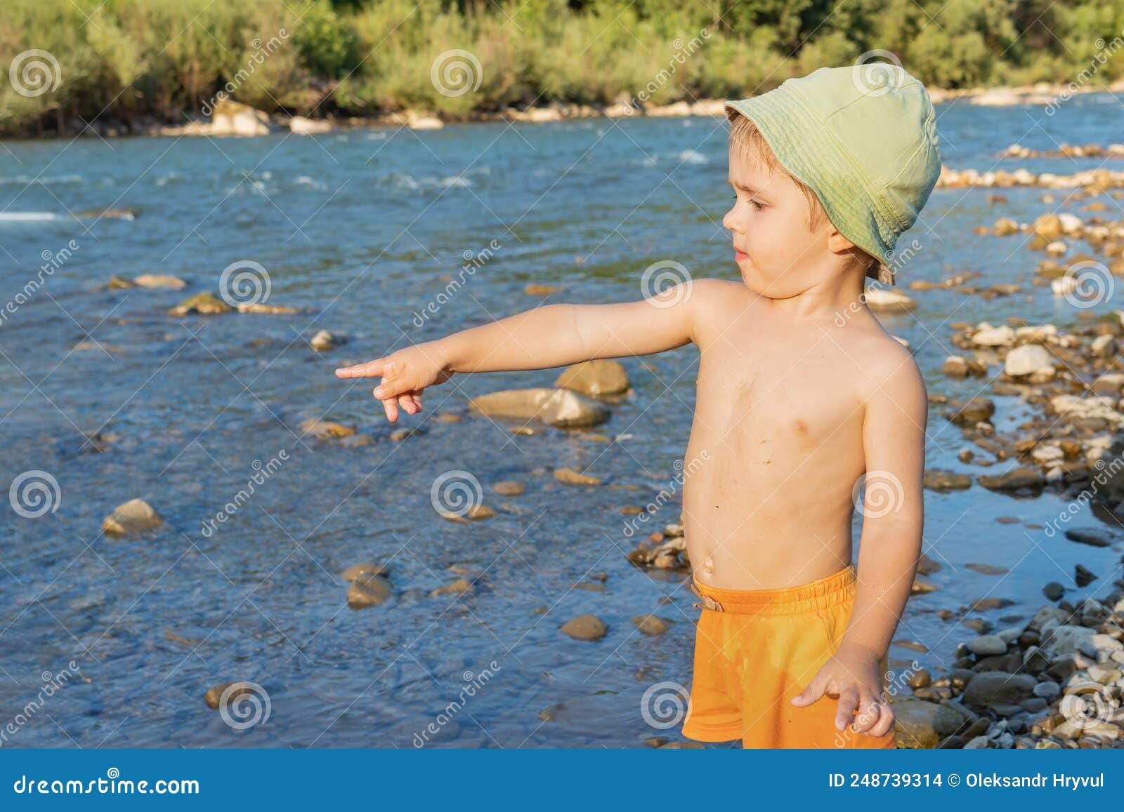 Little Boy Standing by the River. he Points His Finger into the Water ...