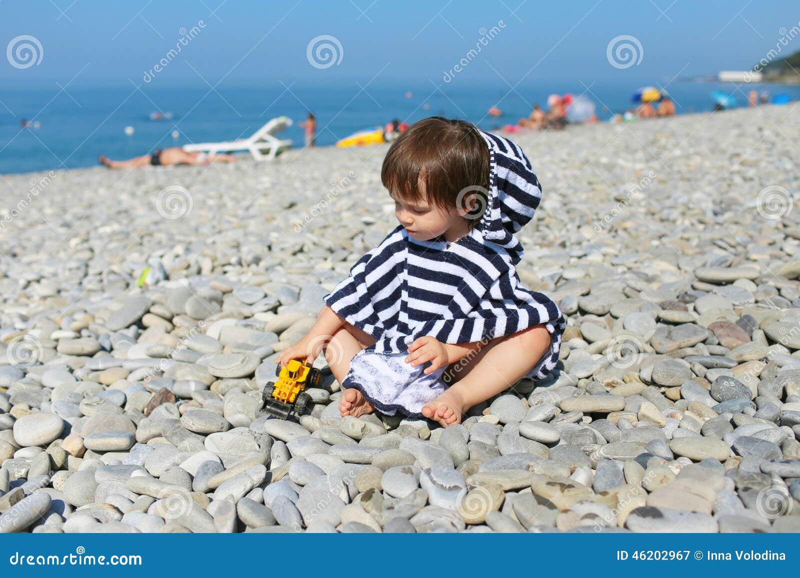 Little Boy in Striped Blanket Sitting on the Pebbles Beach and P Stock ...