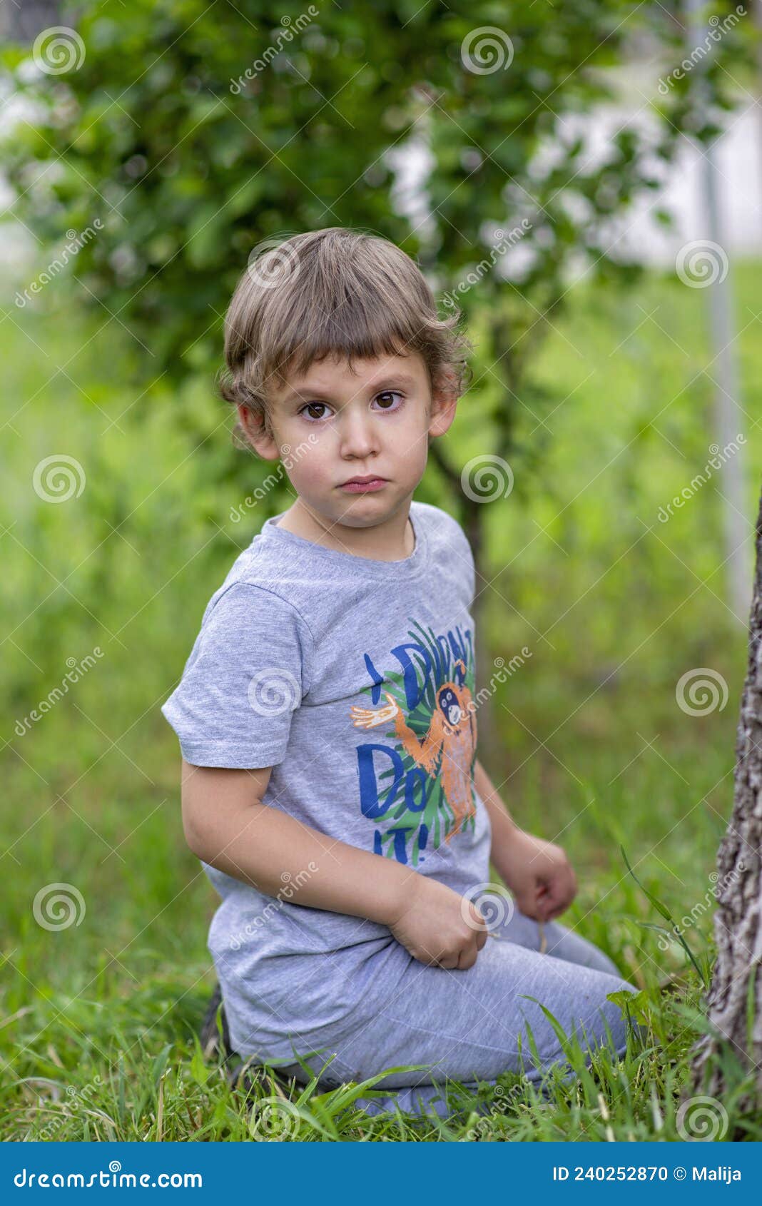 Little Child Sitting on the Grass Alone, Kid with a Sad Face Stock ...