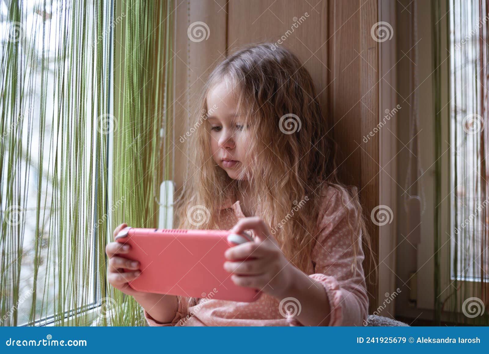 Little Cute Girl Plays a Game Console Sitting on the Windowsill Stock ...