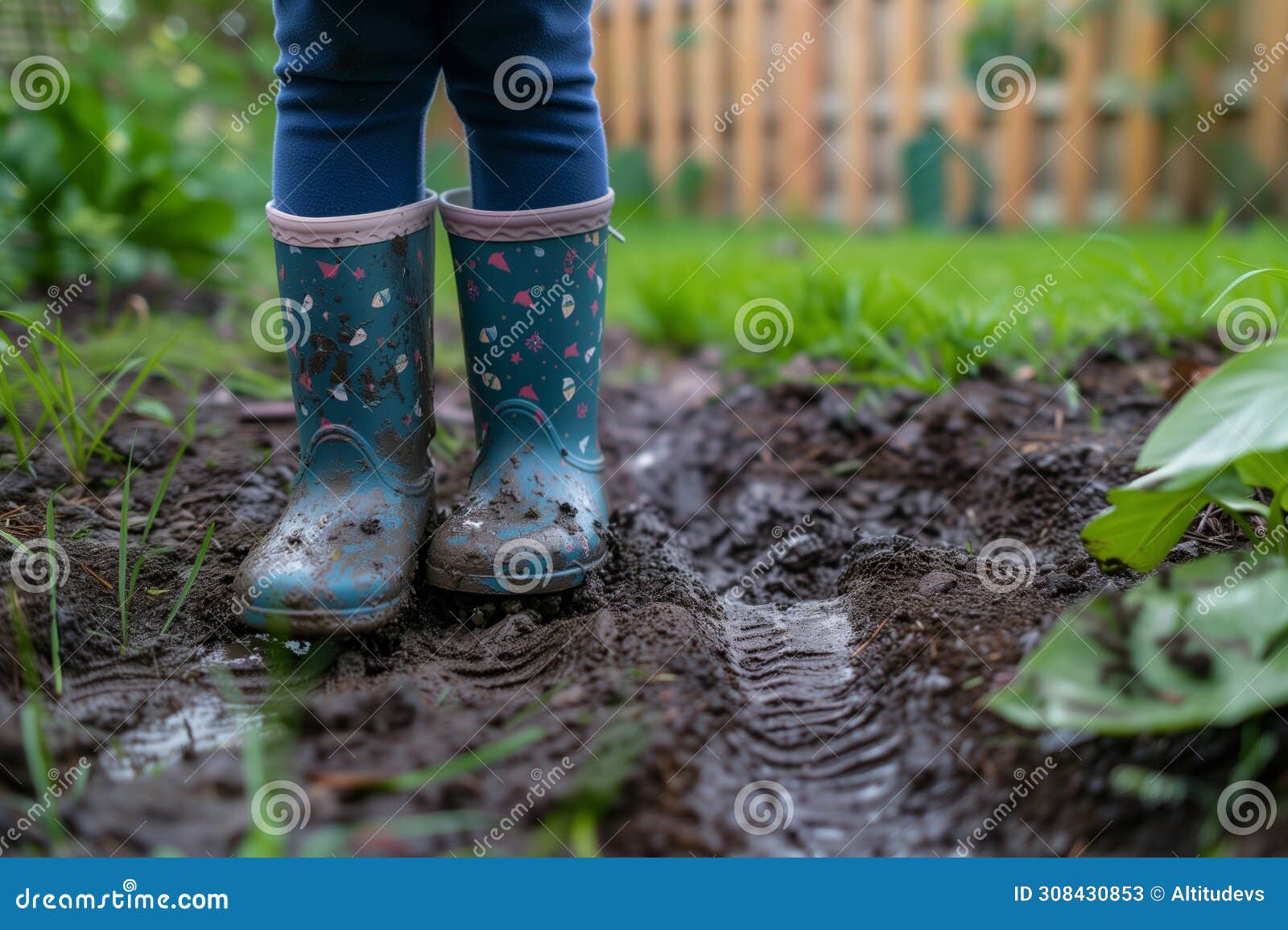 Little Feet in Rain Boots Making Tracks in a Backyard Mud Patch Stock ...