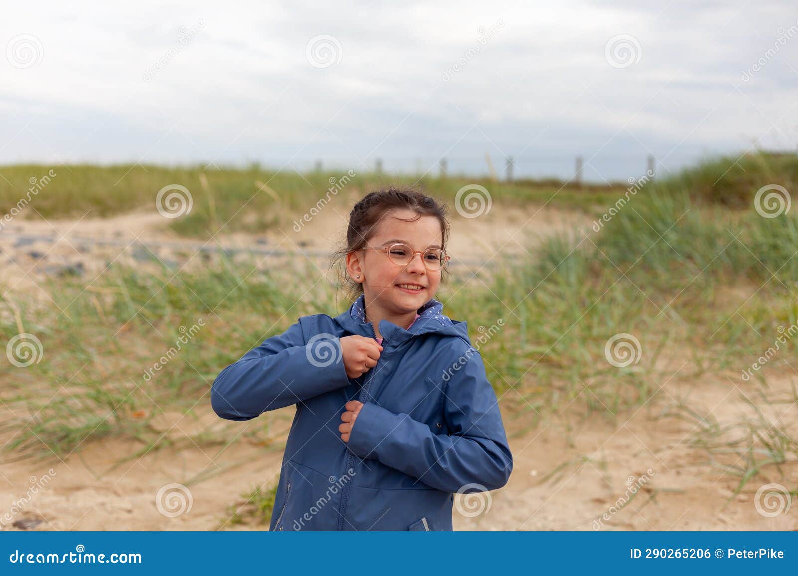 Little Girl in a Blue Jacket on the Beach with Sand Dunes Stock Photo ...