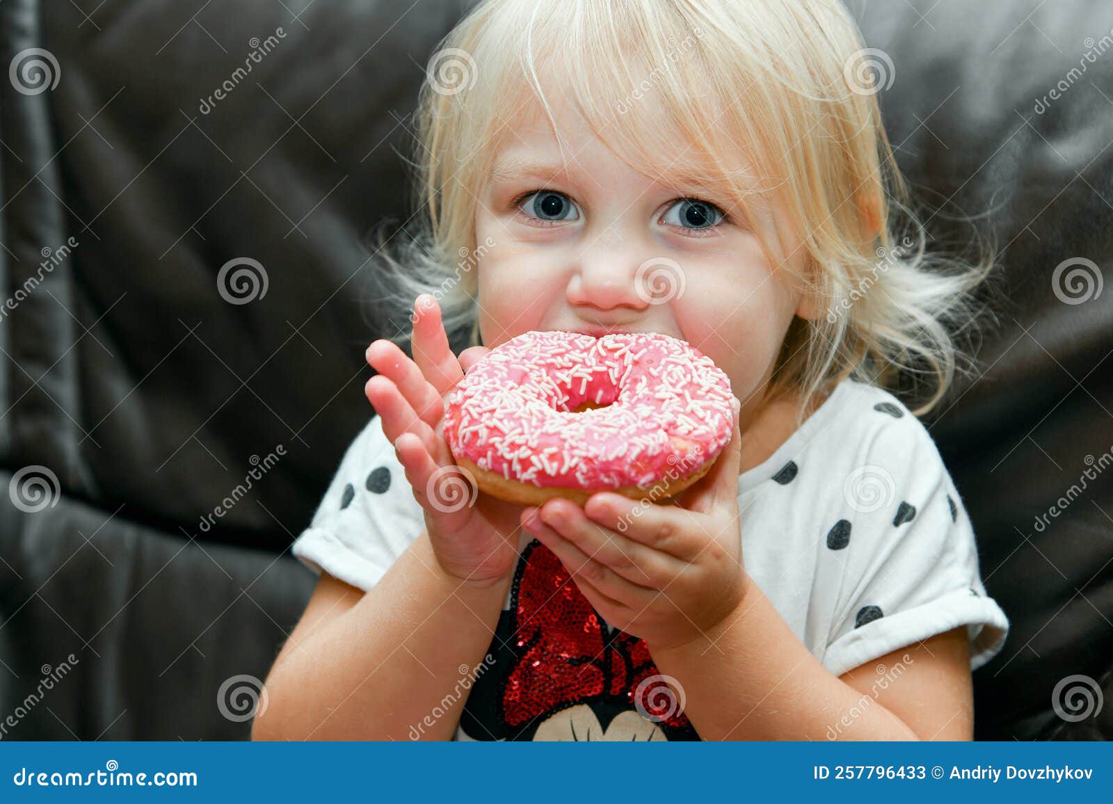 A Little Girl Eats a Delicious Red Donut with Icing Stock Image - Image ...