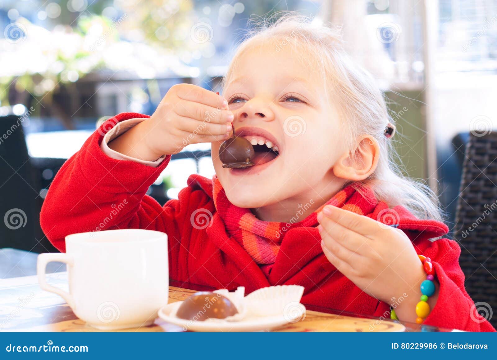 Little Girl Eats Sweets and Drinks Tea in Cafe. Stock Photo - Image of ...