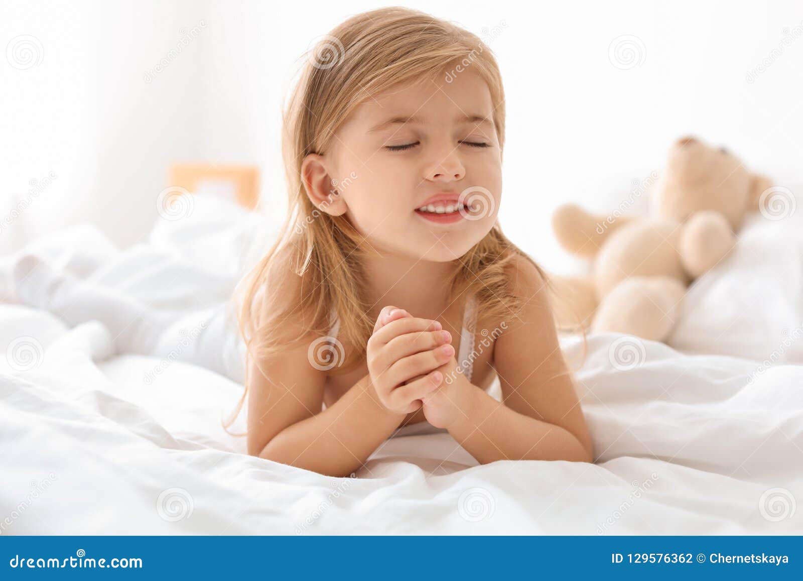 Little girl praying in bed stock photo. Image of belief - 129576362