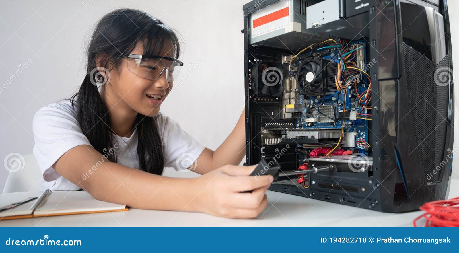 A Little Girl is Repairing Computer Hardware at the White Working Table ...