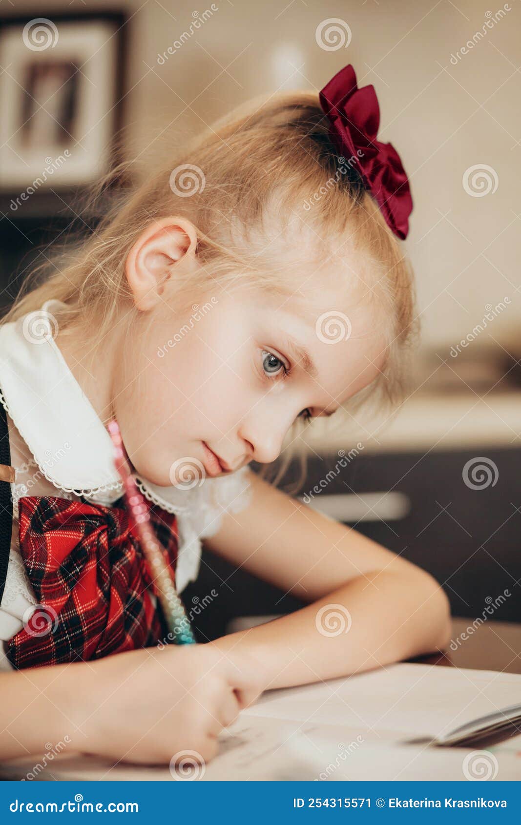 A Little Girl in a School Uniform is Doing Homework in a Exercise Book ...