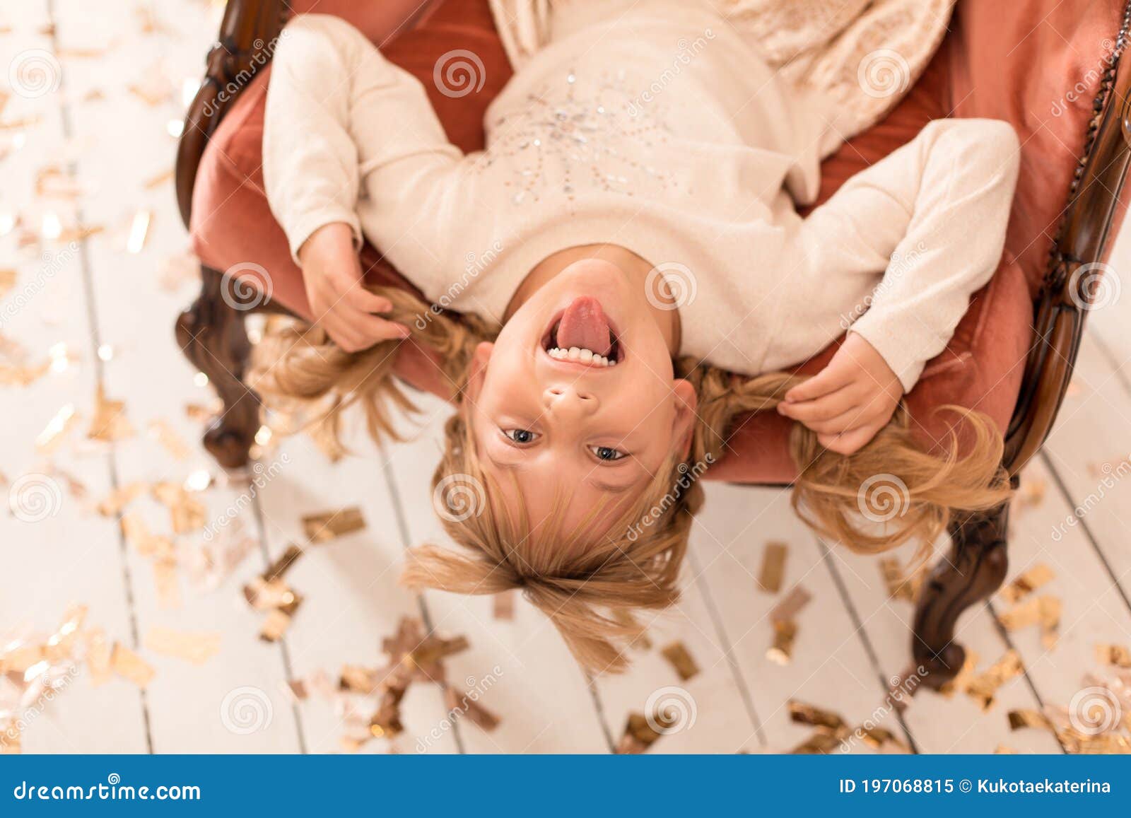 A Little Girl Sits Upside Down in a Chair. a Hyperactive Child Stock ...