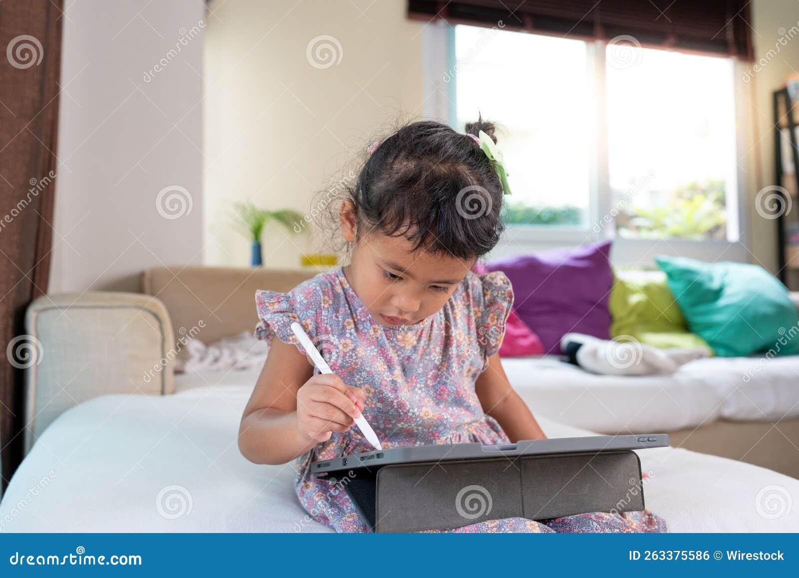Little Girl Sitting on a Couch Using a Tablet Stock Photo - Image of ...