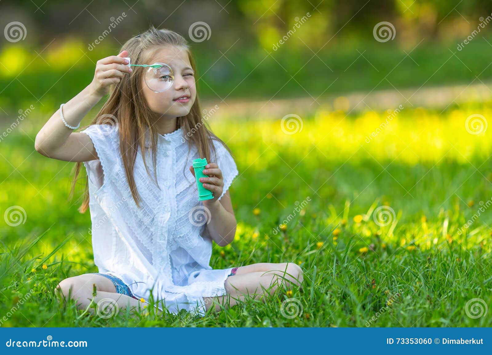 Little Girl Sitting in the Grass and Make Blowing Bubbles. Play . Stock ...