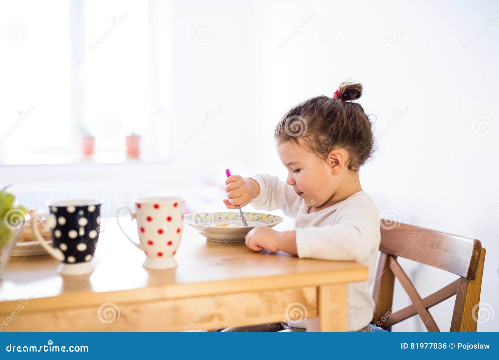 Little Girl Sitting at the Table, Eating Breakfast Stock Photo - Image ...