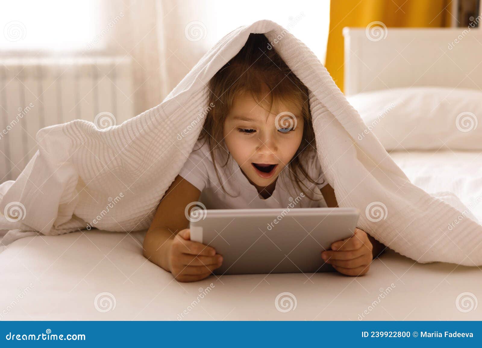 The Girl Under the Blanket Looks at the Tablet. Stock Photo - Image of ...