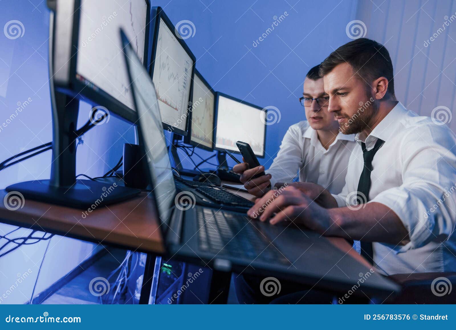 Little Laptop is on the Table with Many Screens. Two Stock Traders ...