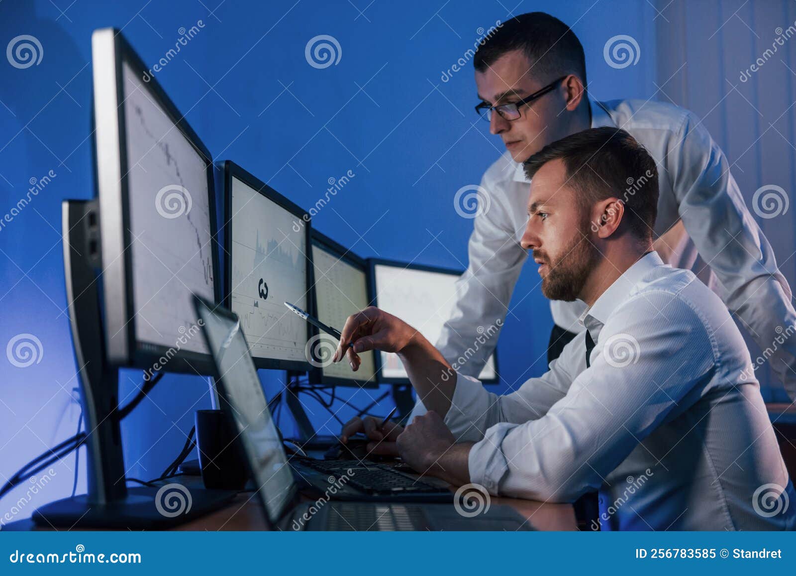 Little Laptop is on the Table with Many Screens. Two Stock Traders ...