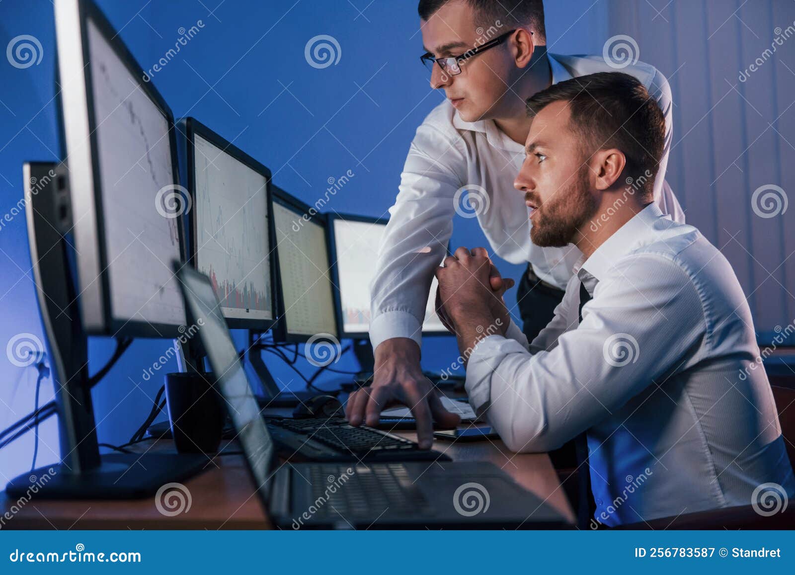Little Laptop is on the Table with Many Screens. Two Stock Traders ...