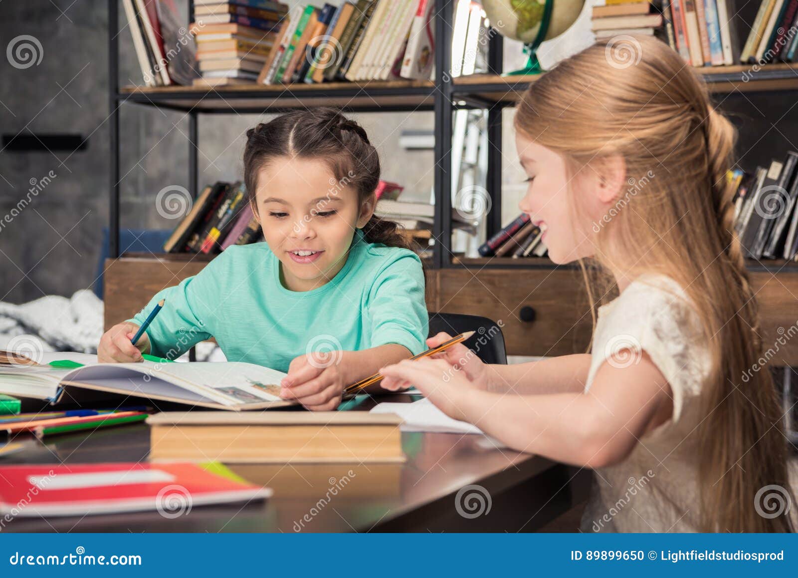 Little Schoolgirls Sitting at Table and Doing Homework Together Stock ...