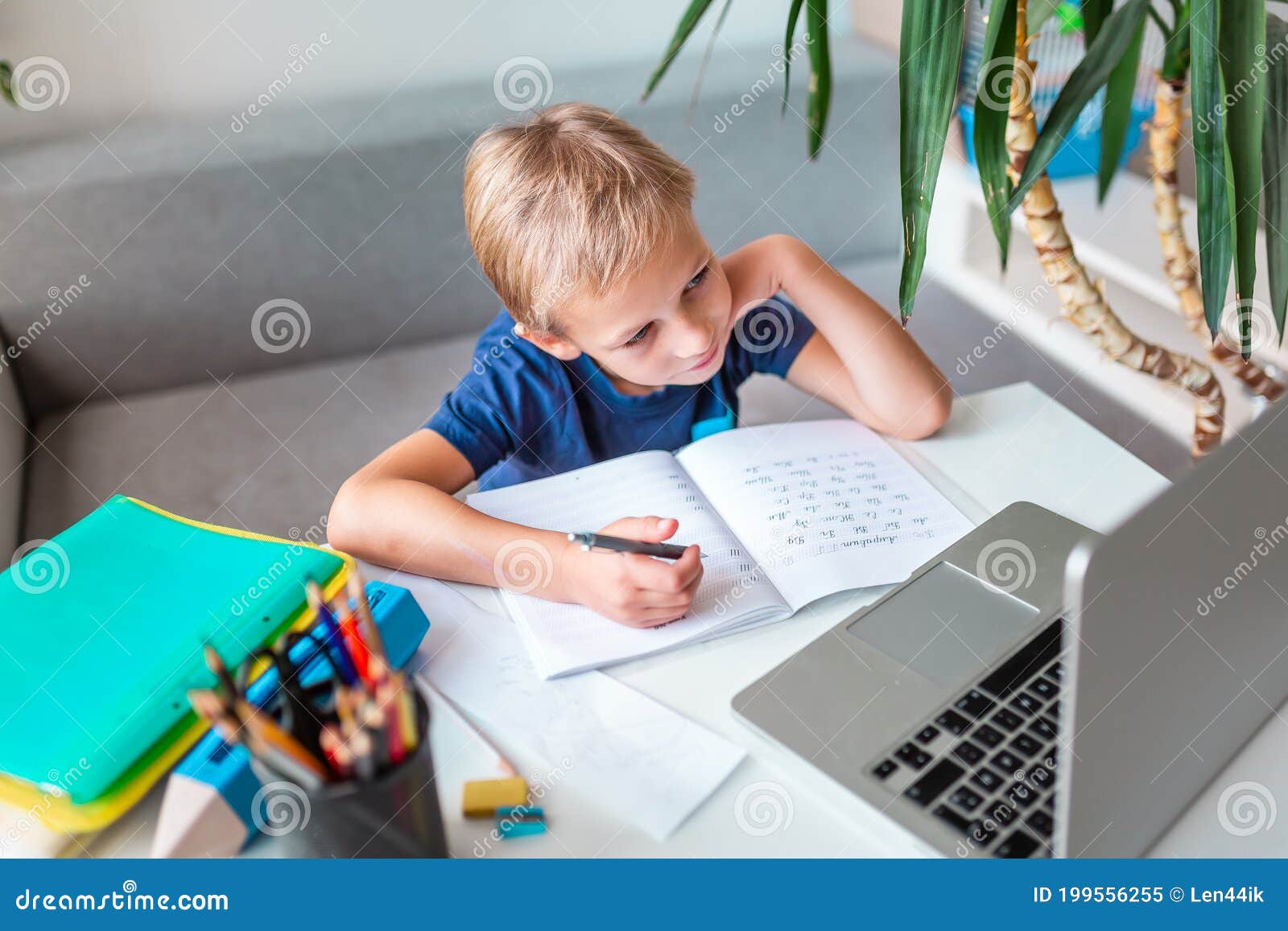 Little Young School Boy Working at Home with a Laptop and Class Notes ...