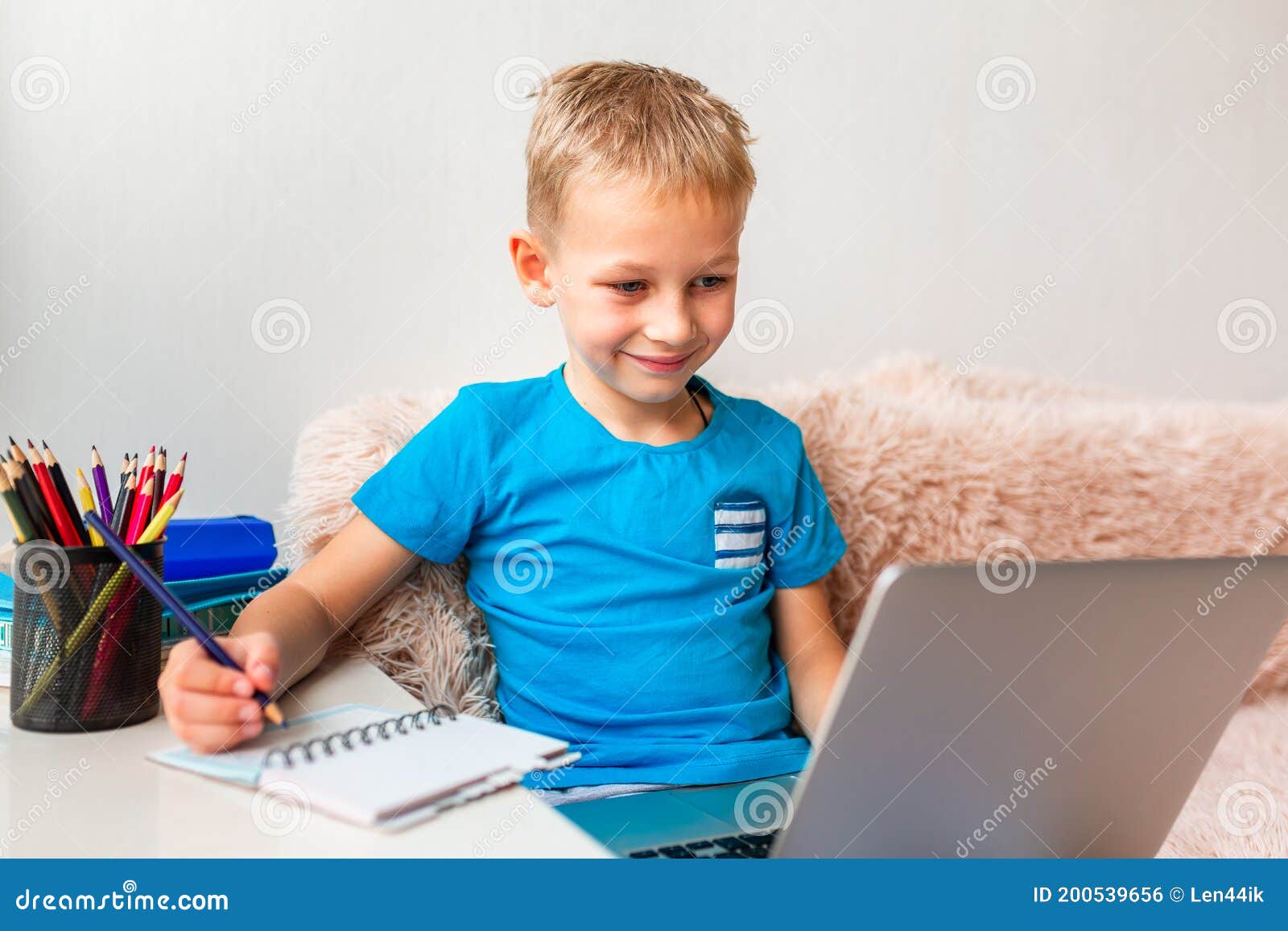 Little Young School Boy Working at Home with a Laptop and Class Notes ...