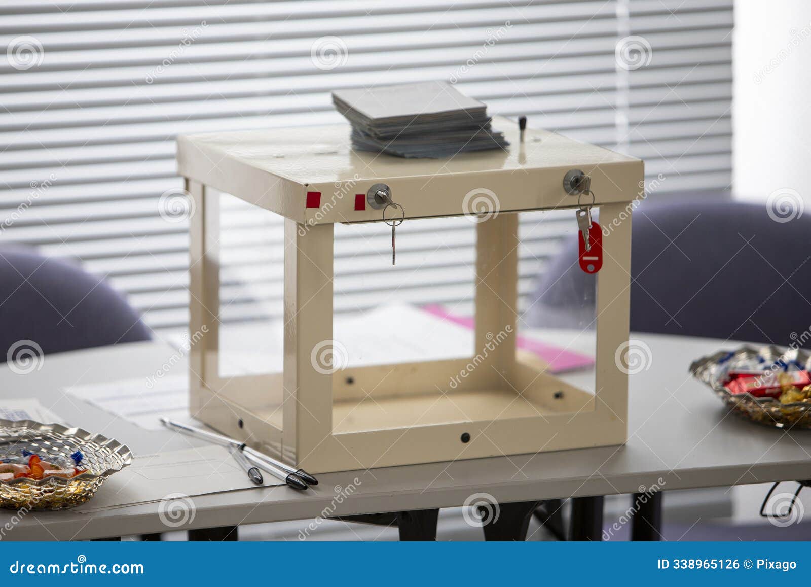 A Locked Transparent Ballot Box with a Stack of Blue Envelopes on Top ...