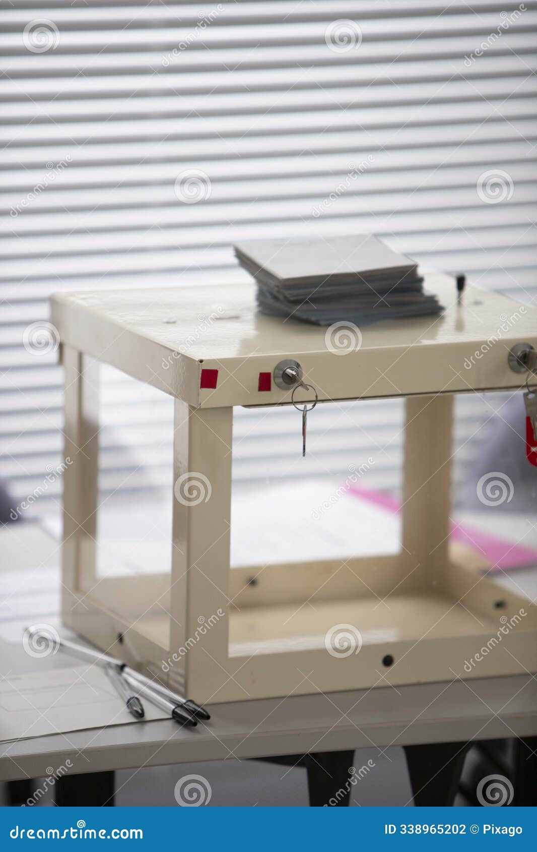 A Locked Transparent Ballot Box with a Stack of Blue Envelopes on Top ...