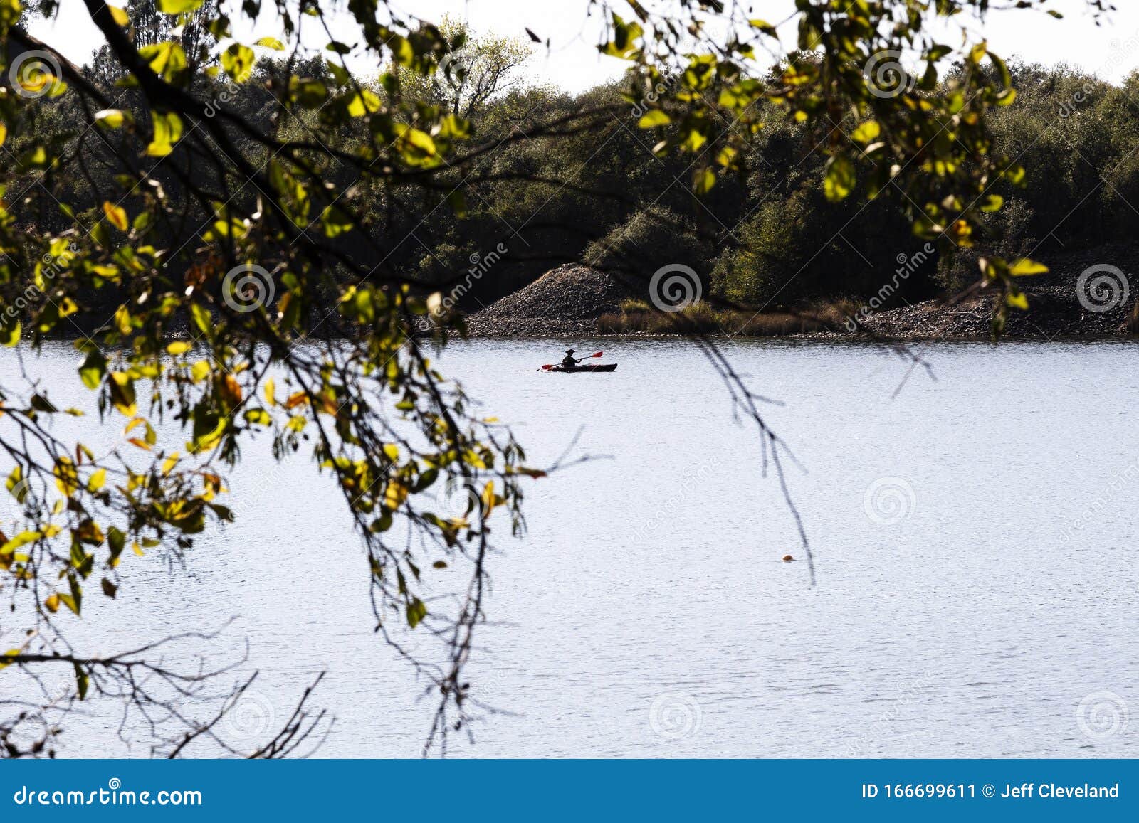 Lone Distant Kayak on River Seen through Branches of Tree Stock Image ...