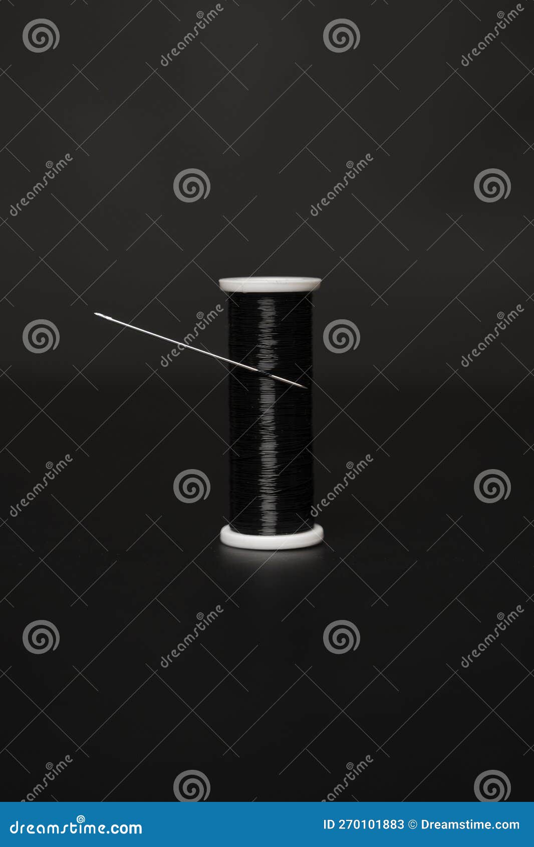 A Lone Spool of Shiny Black Thread with a Pricked Sewing Needle on a ...