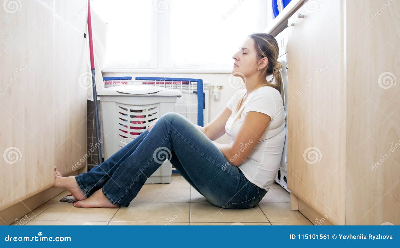 Upset Lonely Housewife Sitting On Floor After Doing Laundry Stock Image