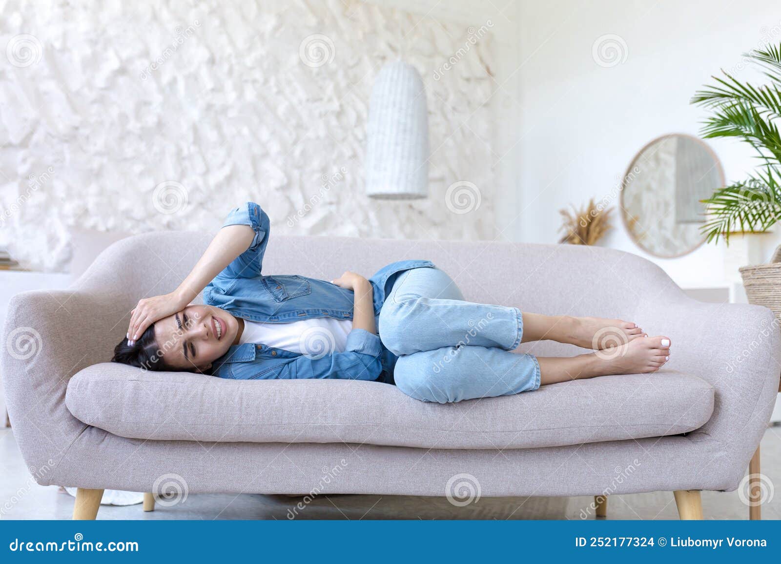 Lonely And Sick Beautiful Woman Alone At Home Lying On Sofa Holding