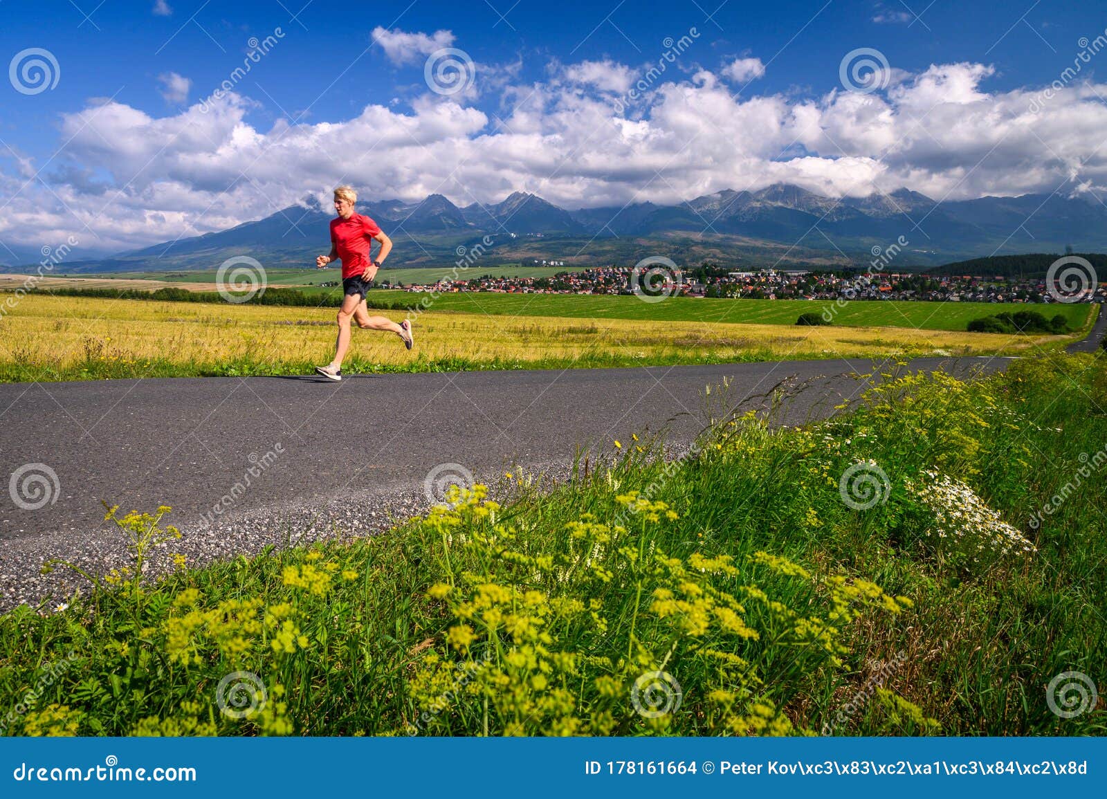 Long Distance Runner Train on the Road Under Big Mountains. Summer Day ...