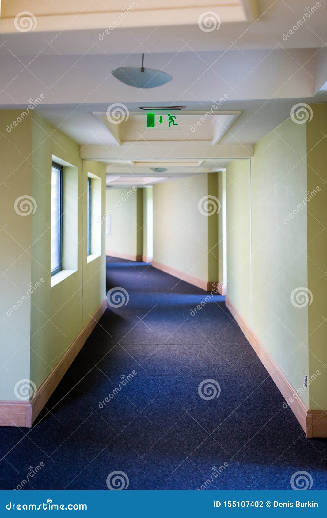 Long Empty Corridor with an Emergency Exit Sign Stock Photo - Image of ...