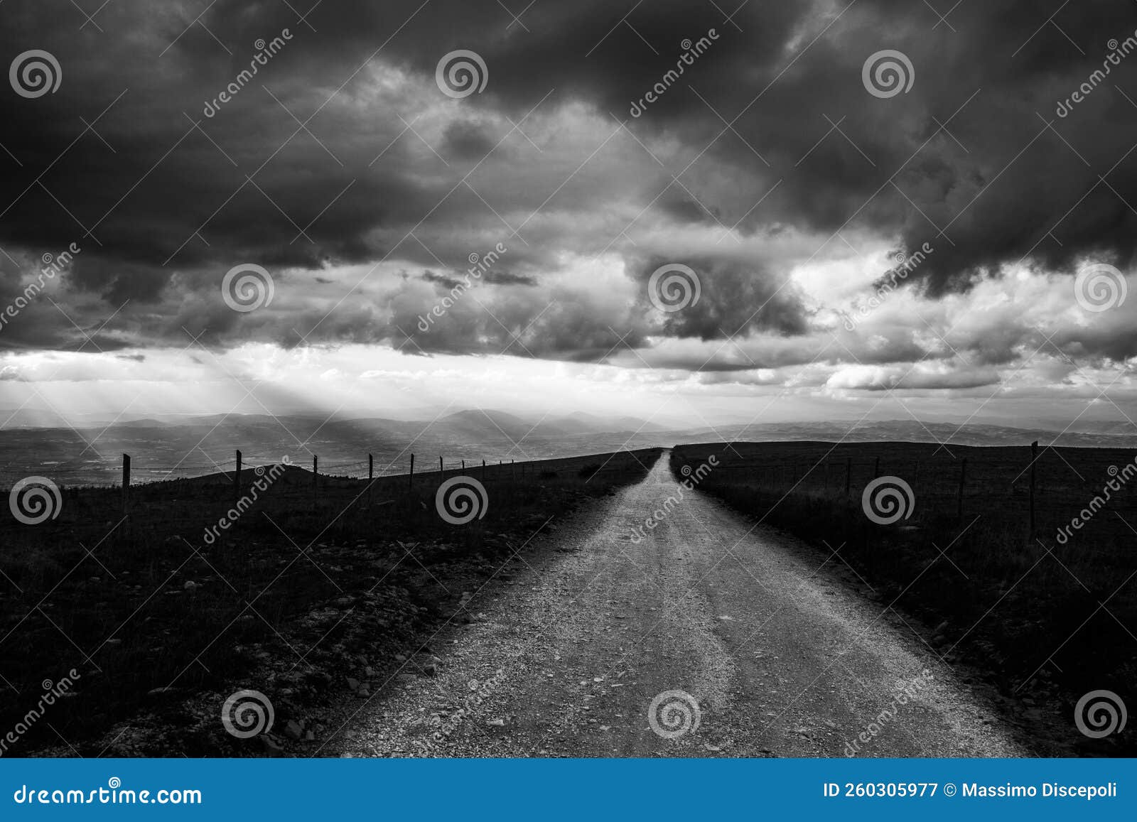 A Long, Endless Mountain Road Beneath a Moody Sky with Distant Sunrays ...