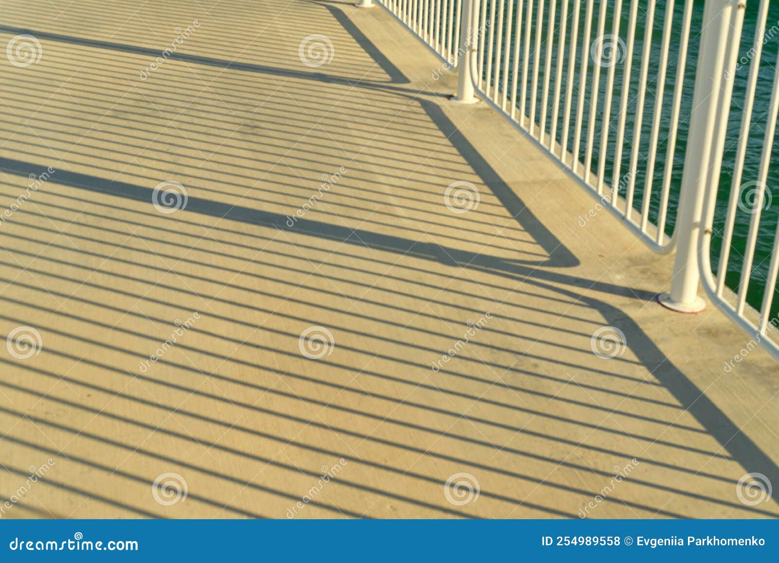 Long Evening Shadows from the Railing on the Pier. Stock Photo - Image ...
